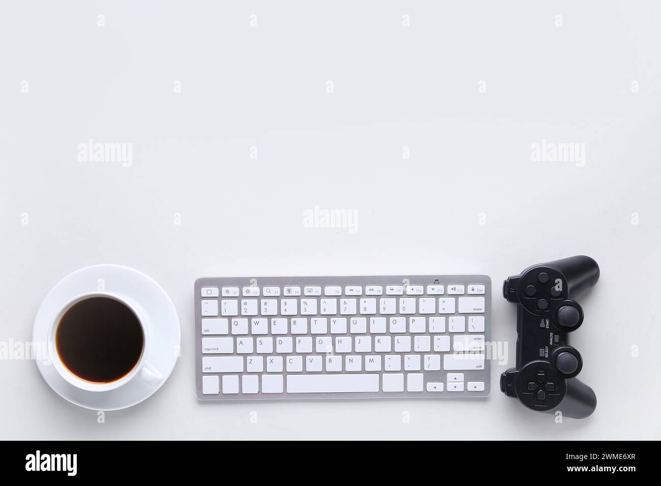 Modern computer keyboard, cup of coffee and joystick on white ...