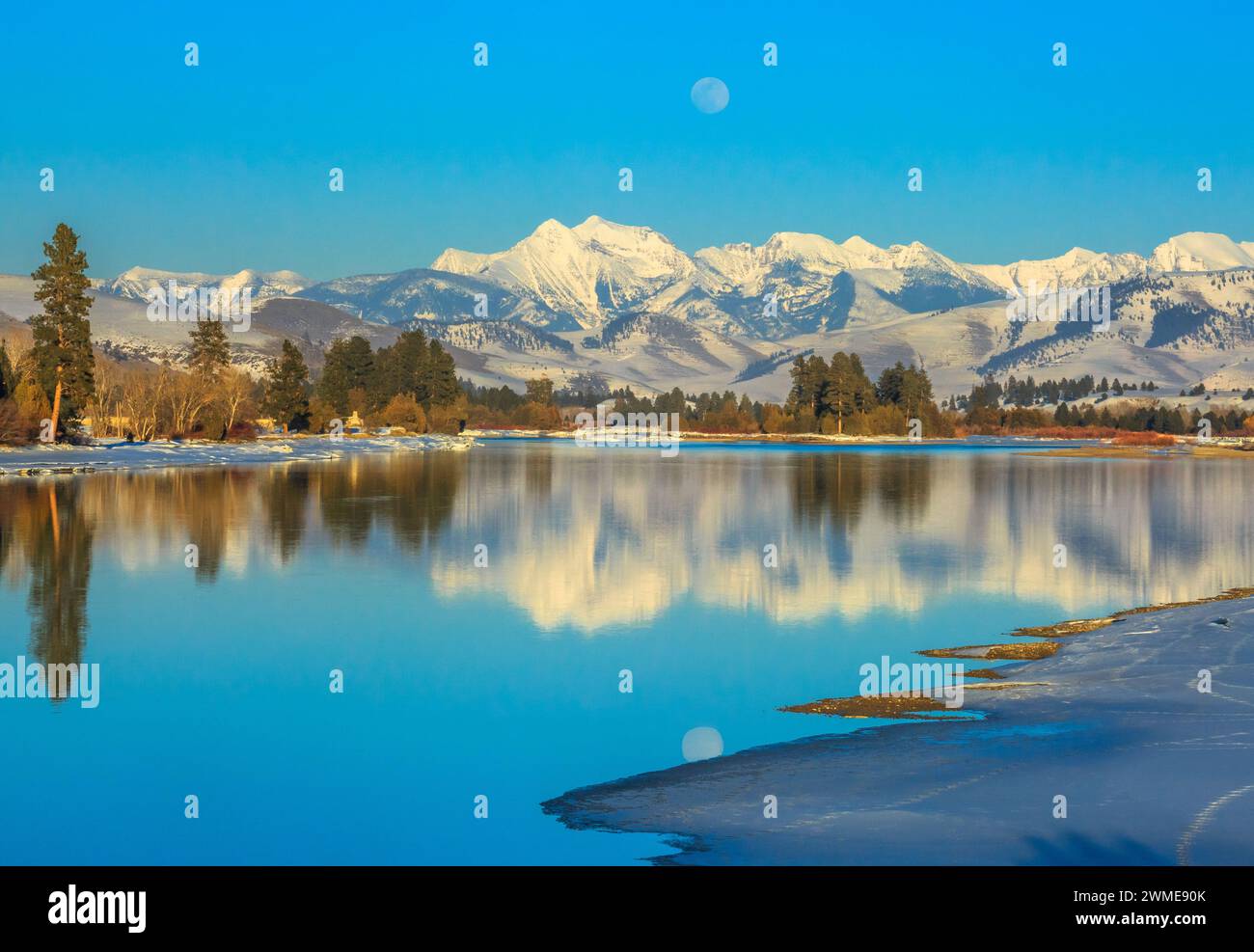 full moon above the flathead river and mission mountains in winter near ...