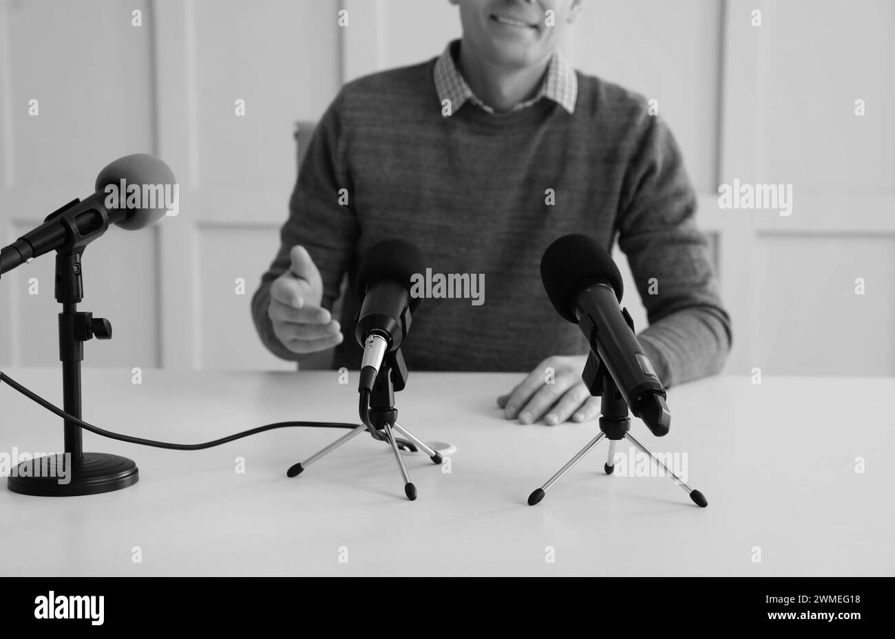 Journalist conference. Man giving interview at table with microphones ...