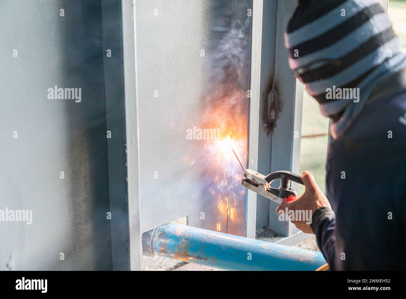 A metal welder welds metal a wall in a warehouse. Metal welding process ...