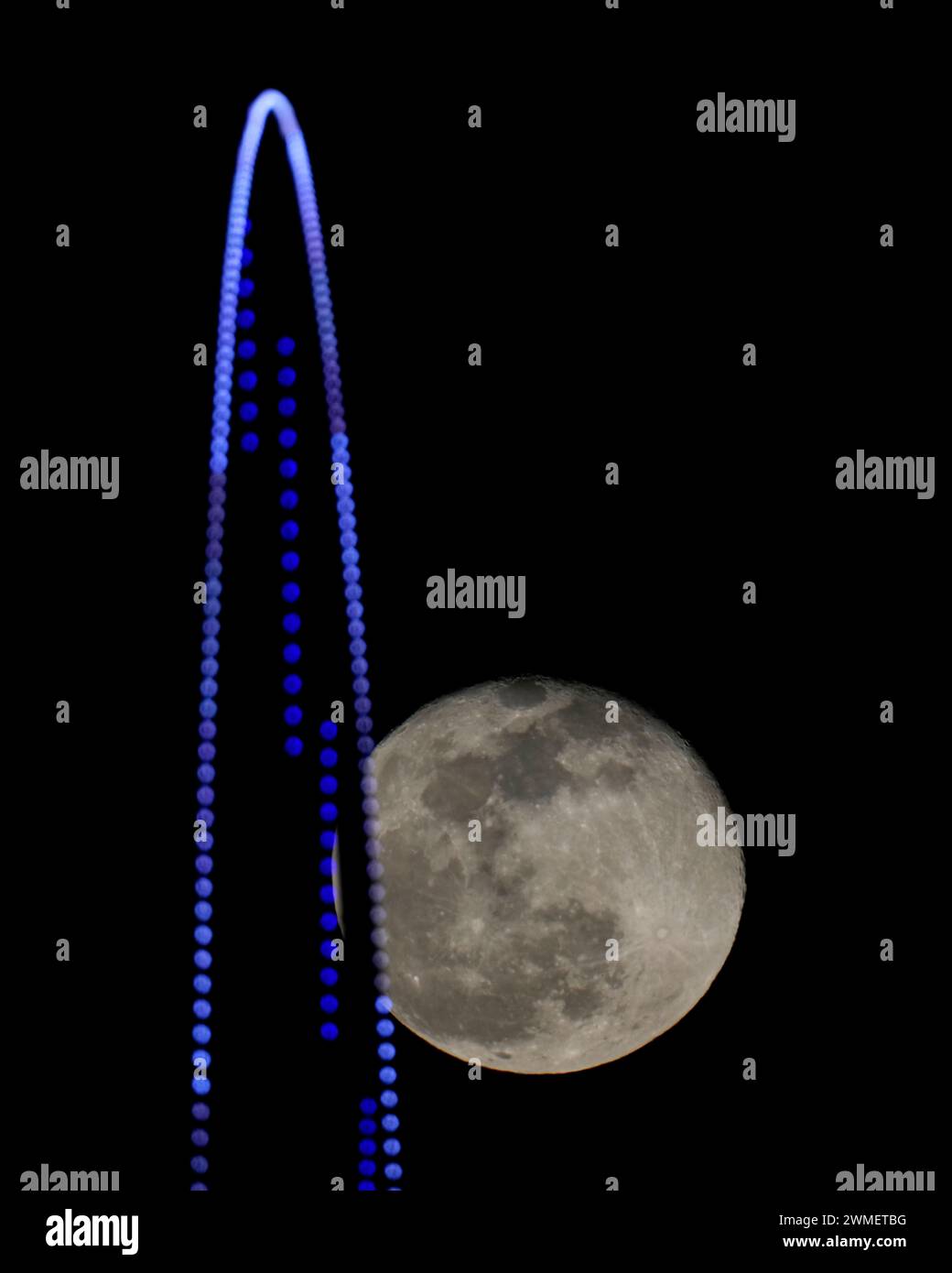 The waning moon rises beyond a Ferris wheel Sunday, Feb. 25, 2024, in ...