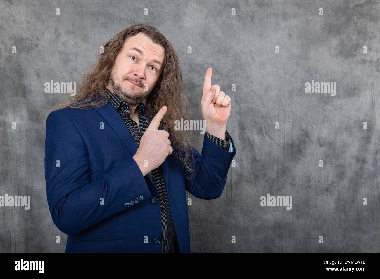 The stylish man with long hair in a striking blue suit posing in ...