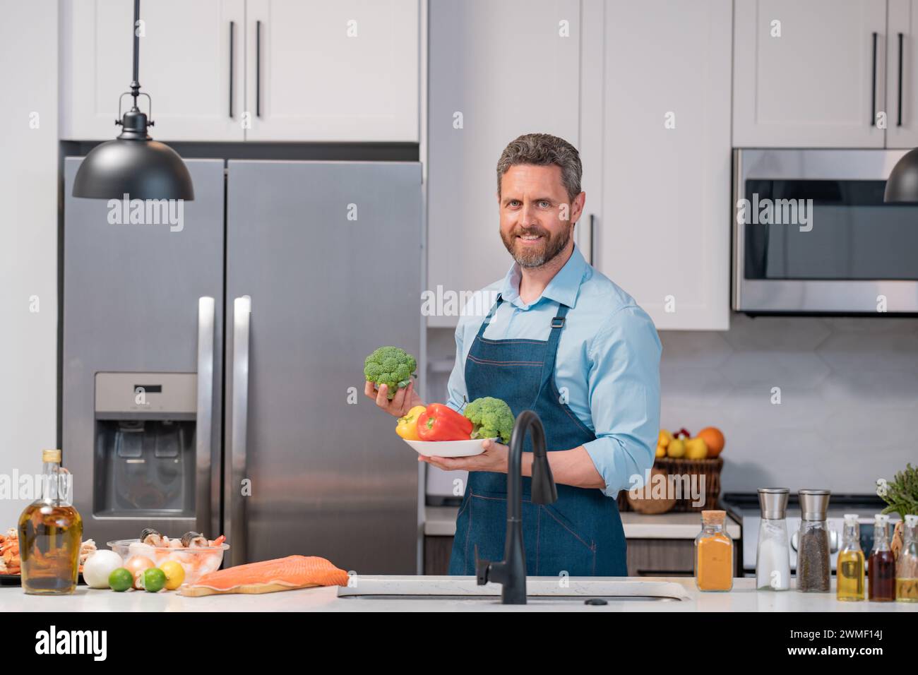 Chef in cook apron cooking in kitchen. Man on kitchen with vegetables ...