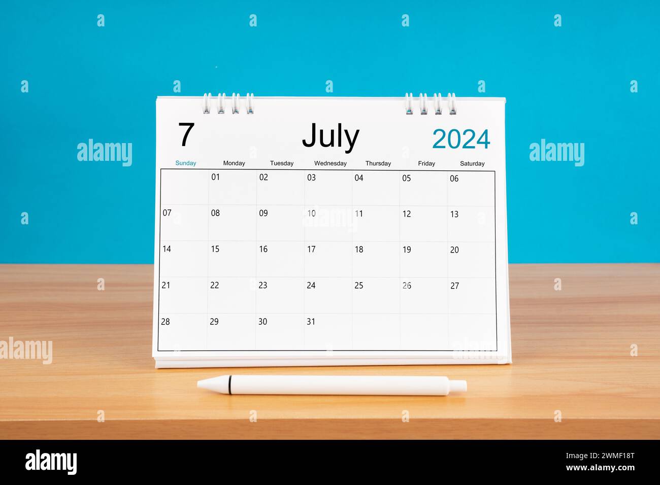 July monthly desk calendar for 2024 year and pen on wooden table with ...
