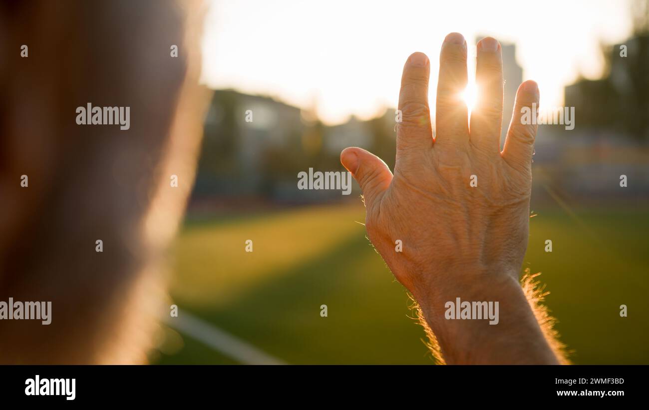 Old man grandfather pensioner looking sunrise sun through palm hand ...