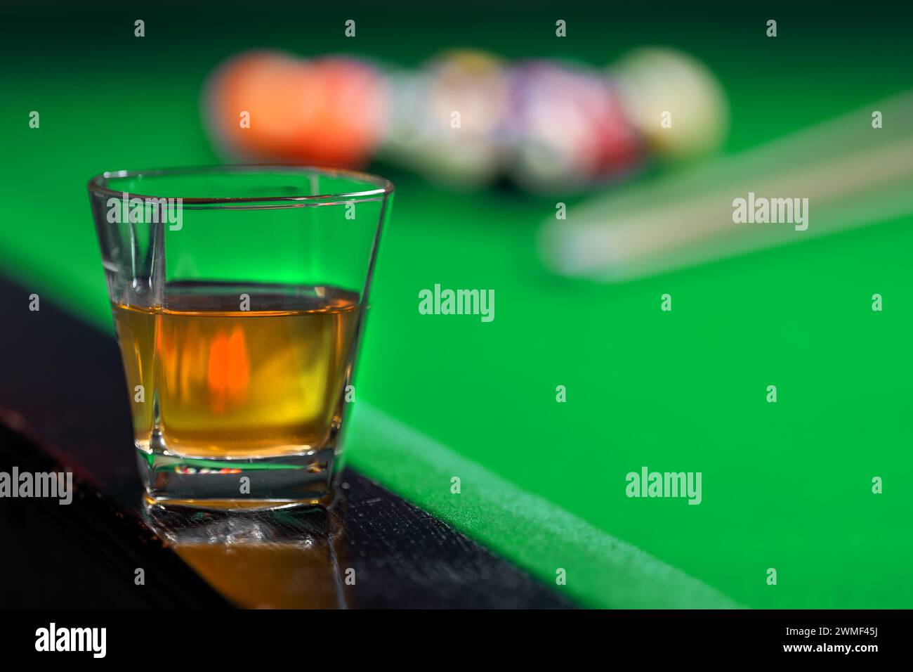 Two glass of whiskey on billiard table and billiard balls in background ...