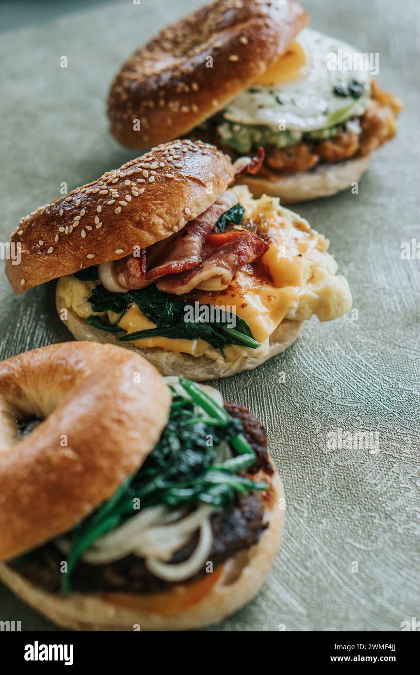 Top-down view of three breakfast sandwiches stacked toasted bagels with ...