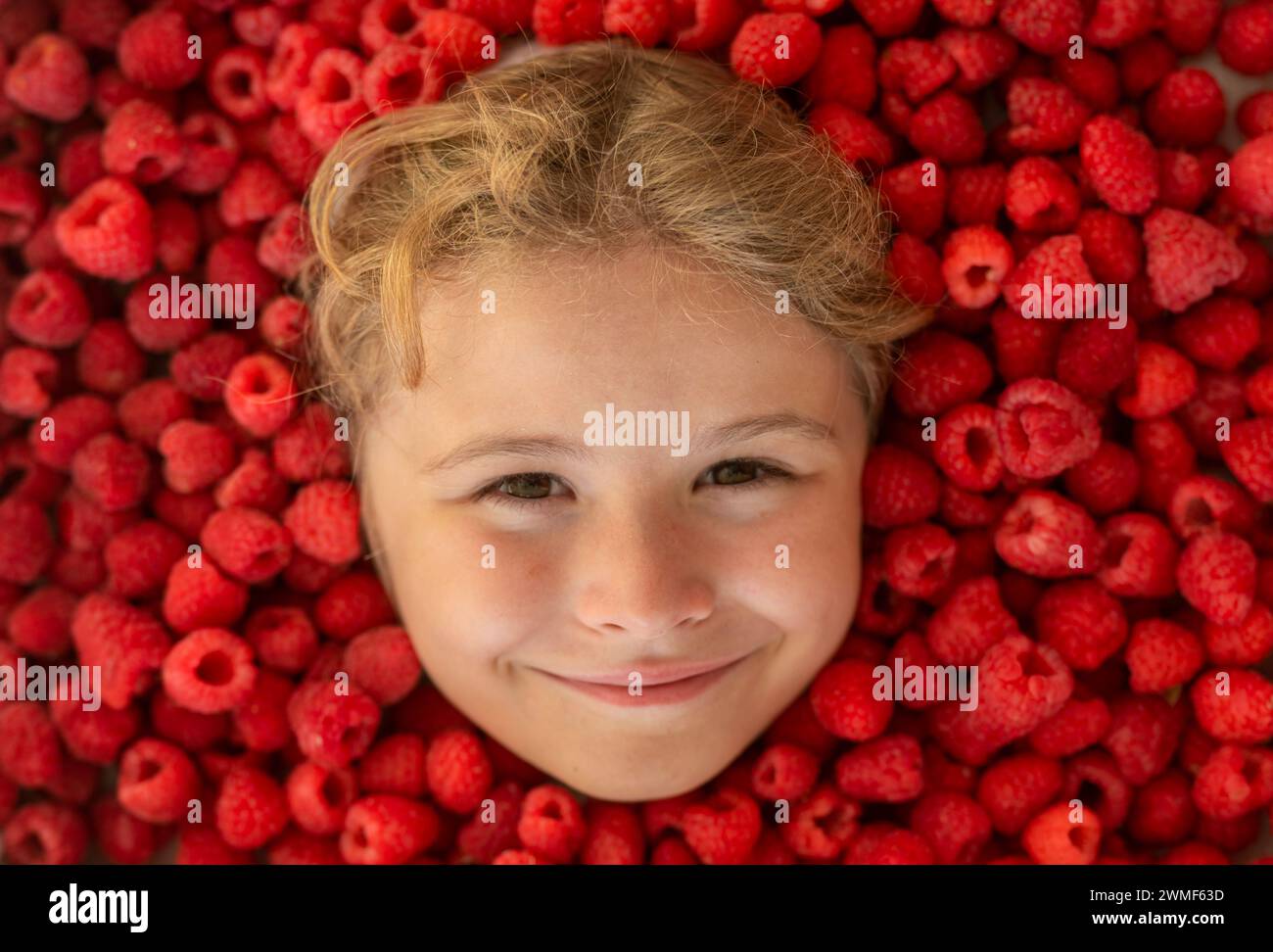 Top view photo of child face in raspberries background. Healthy eating ...