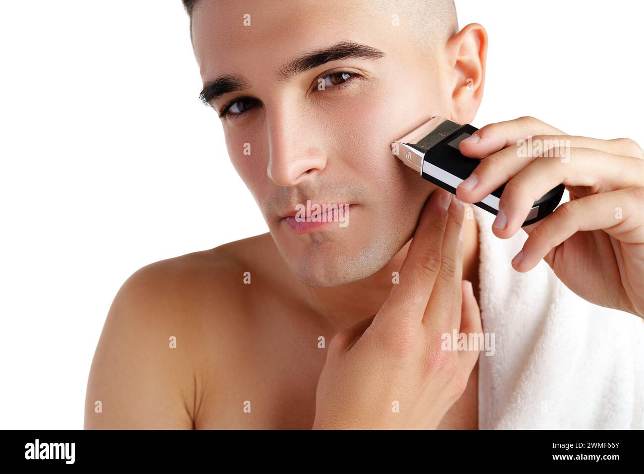Handsome young man shaving face with electric razor on white background ...
