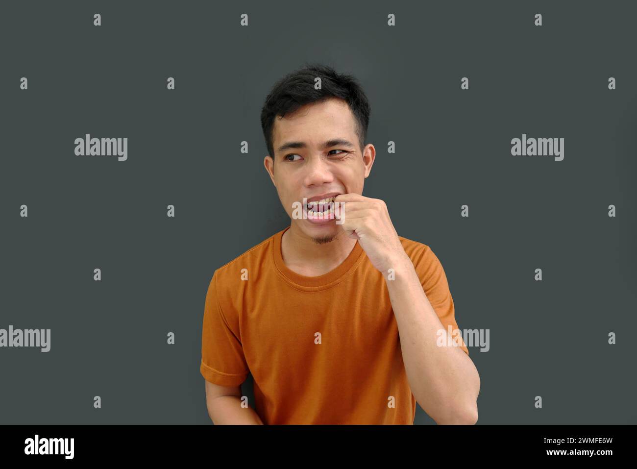 Something stuck in the teeth of a young Asian man, pulling with a hand ...