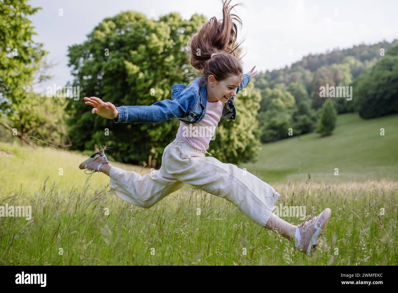 Beautiful young girl jumping in tall grass, having fun, enjoying warm ...