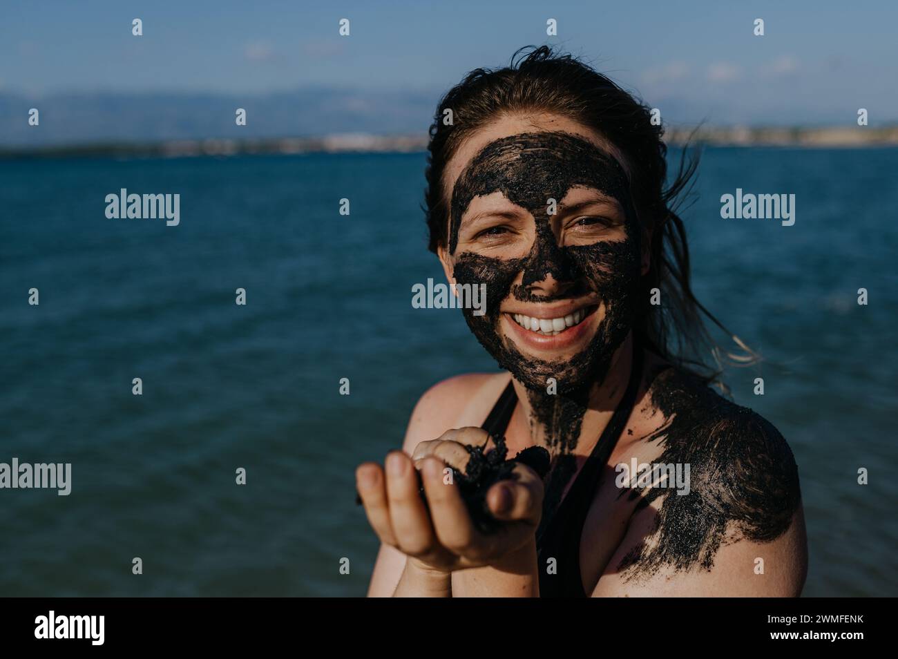 Woman applies healing mud to her face and body. Natural healing mud in ...
