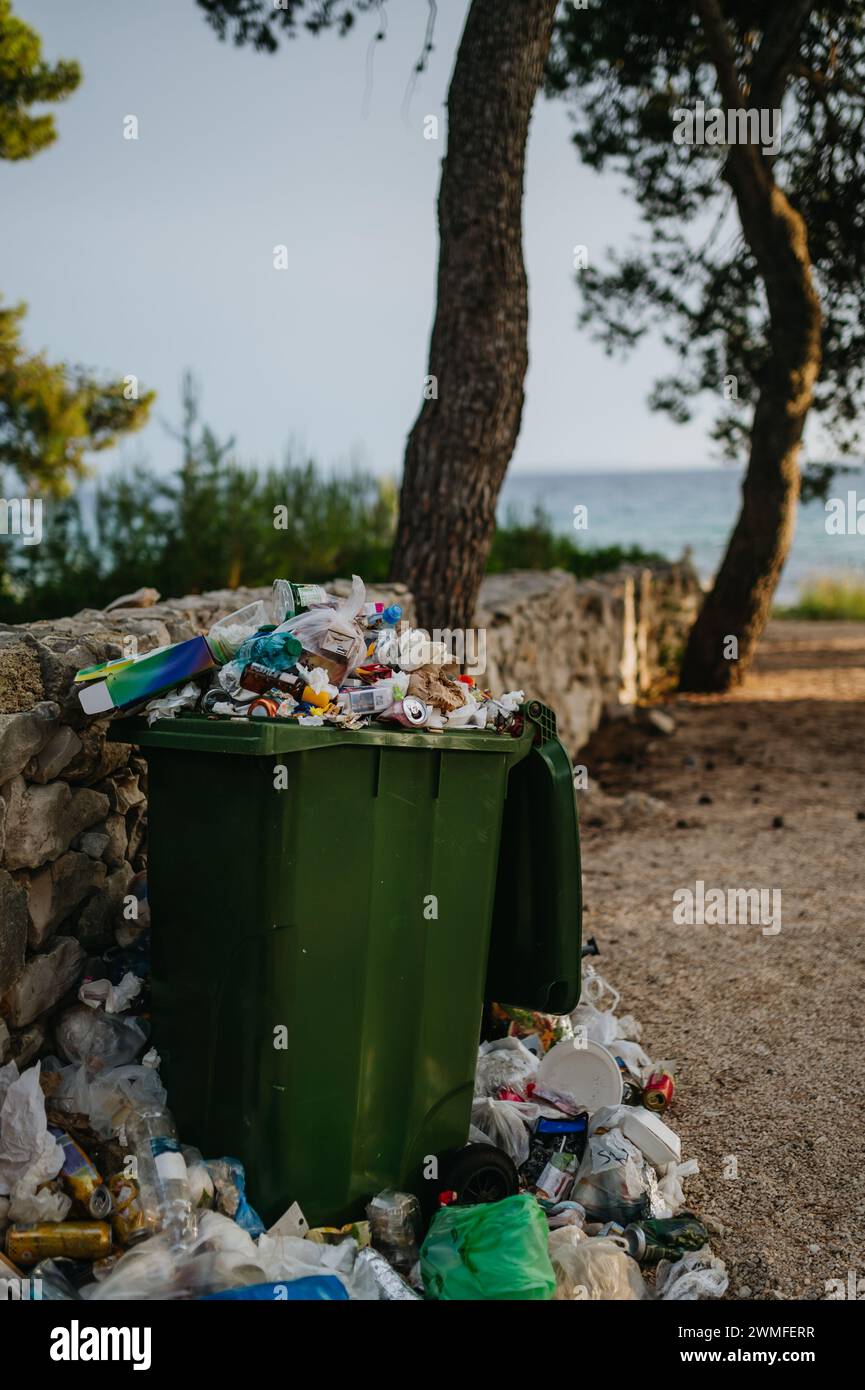 Trash in the street spilling on to the pavement. Full bins in holiday ...