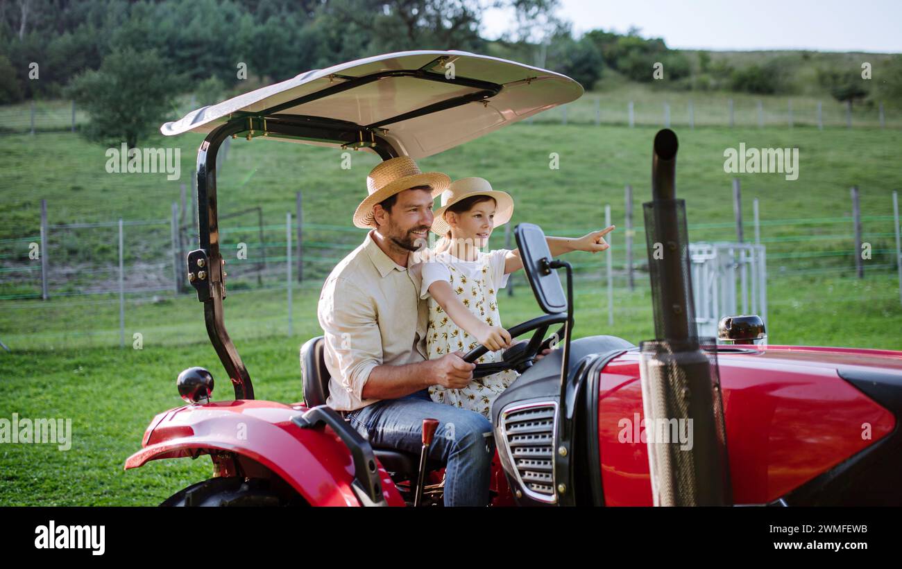 Farmer father riding tractor with his daughter. Girl growing up on ...