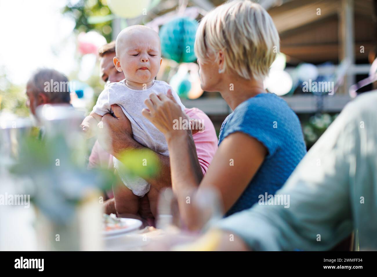 Cute baby eating something sour at summer garden party Stock Photo - Alamy