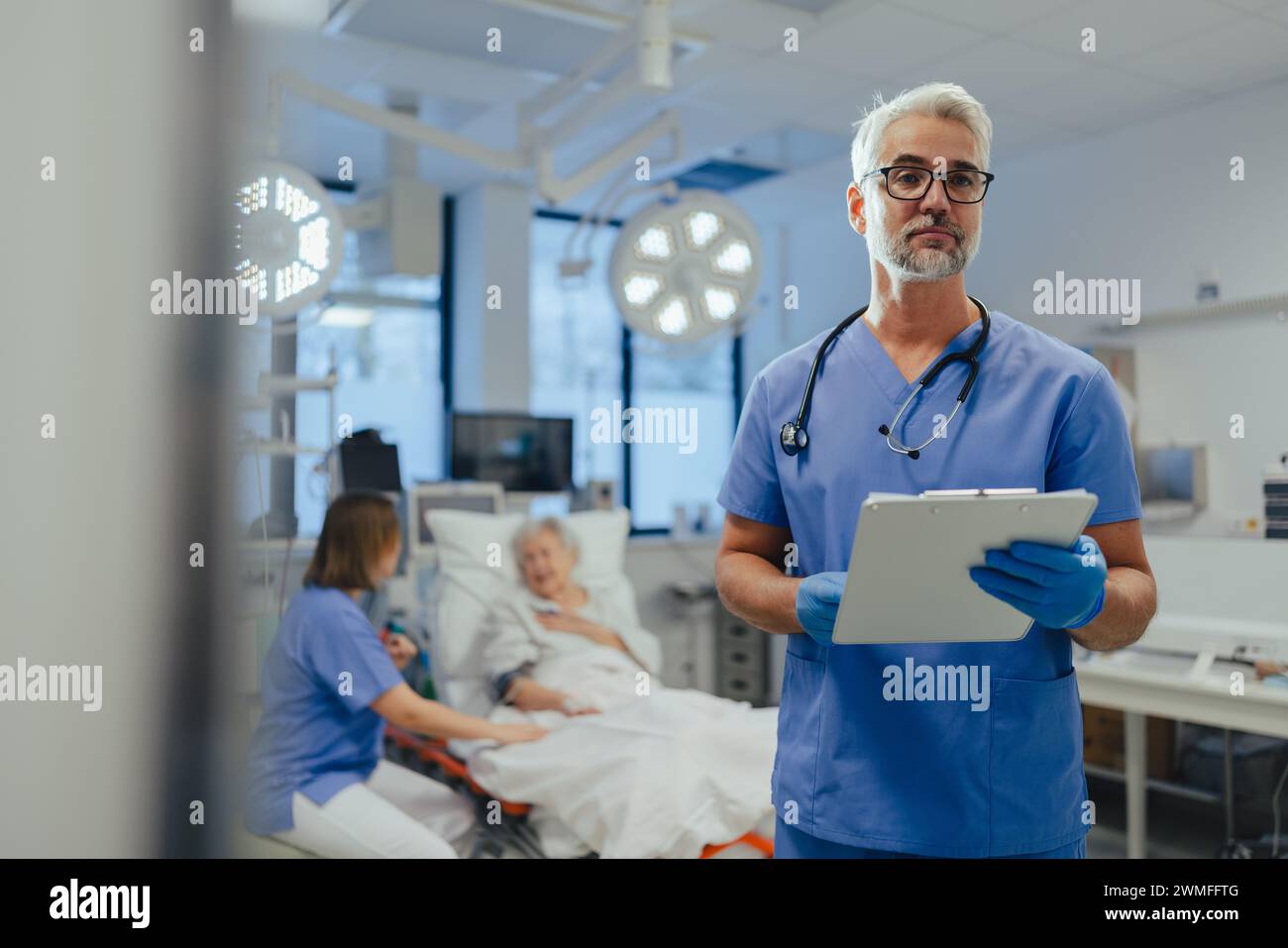 Portrait of handsome male doctor, patient in hospital bed behind. ER ...