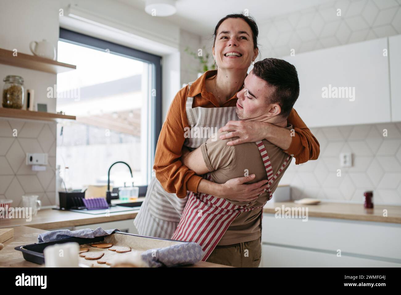 Young man with Down syndrome baking cookies with his mother at home ...