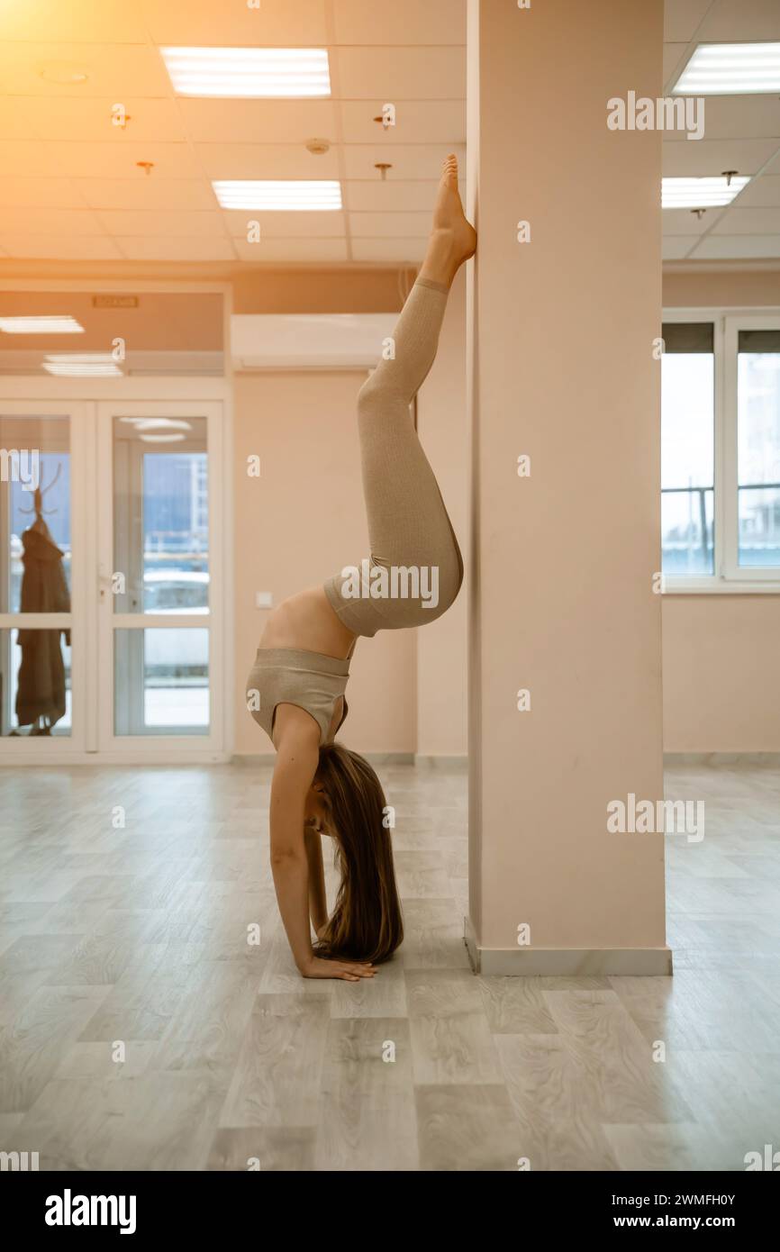 The girl is training in the yoga studio. Dressed in a beige tracksuit ...