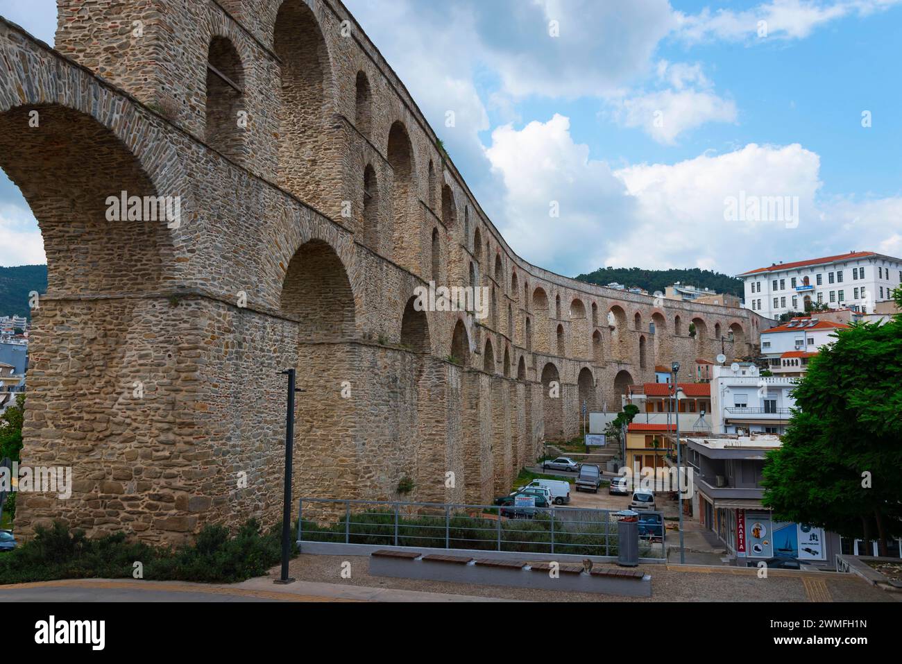 A Roman aqueduct spans a modern cityscape under a cloudy sky, Kavala ...