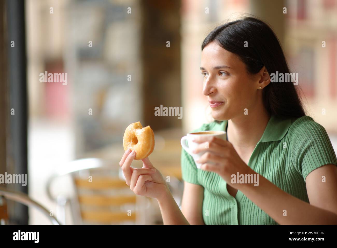 Restaurant customer at breakfast eating doughnut and drinking coffee ...