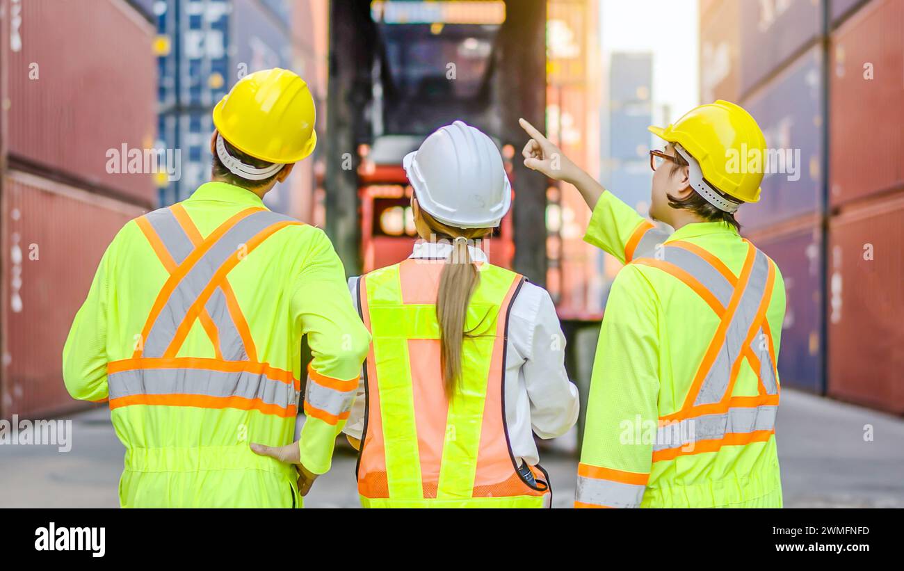 The dock workers in safety gear stand in front of massive containers ...