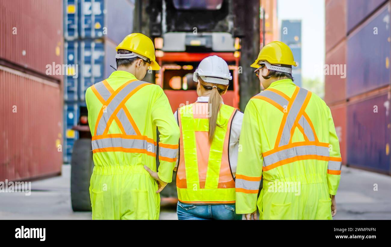 The dock workers in safety gear stand in front of cargo containers ...