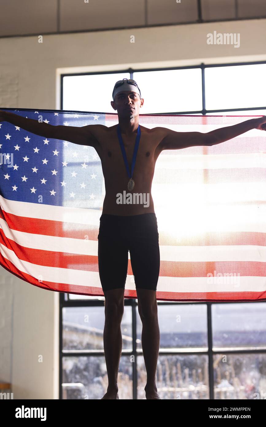 Proud young biracial male athlete swimmer displays the American flag ...