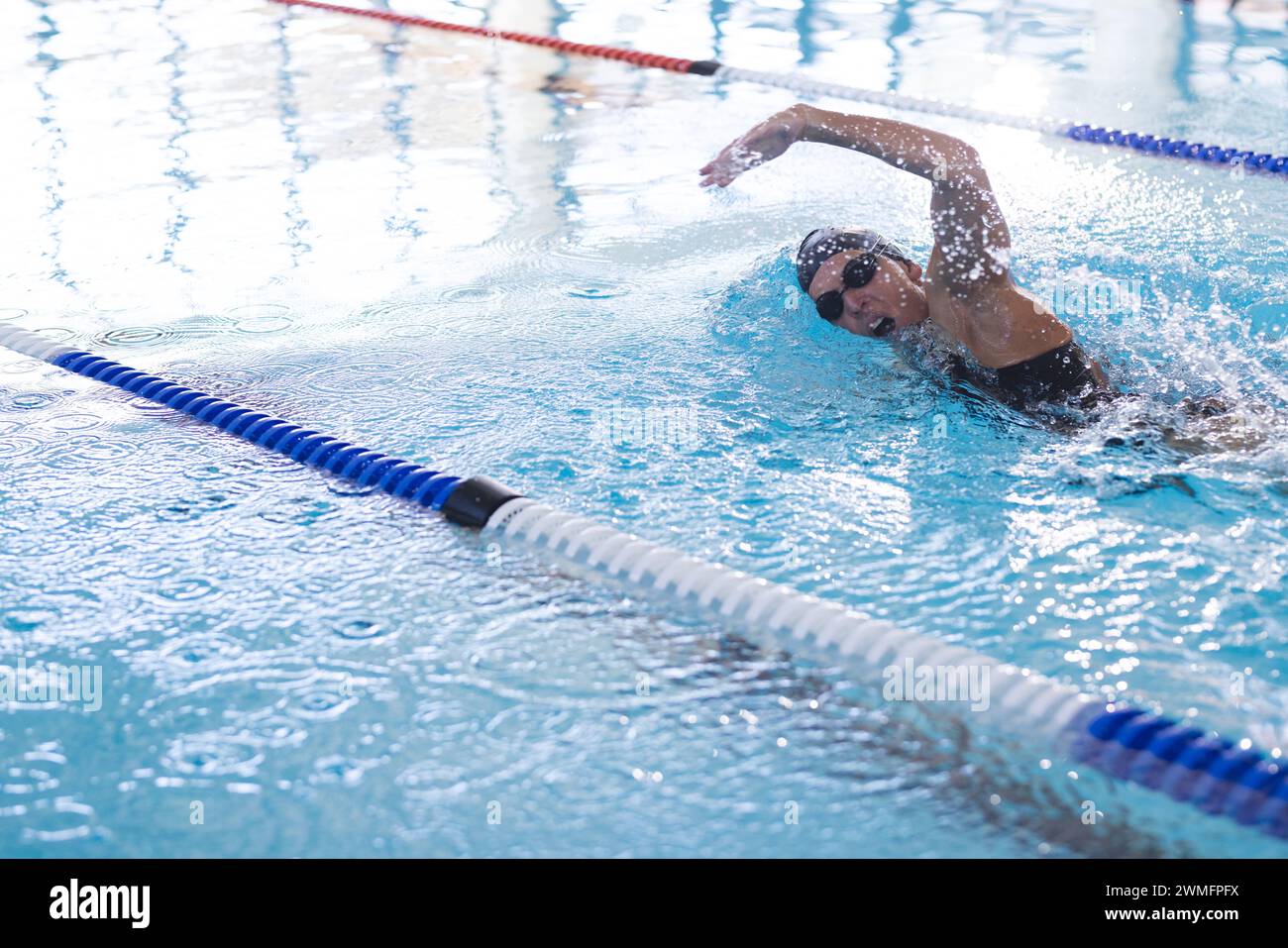 Caucasian female athlete swimmer swims in an indoor pool. She's ...