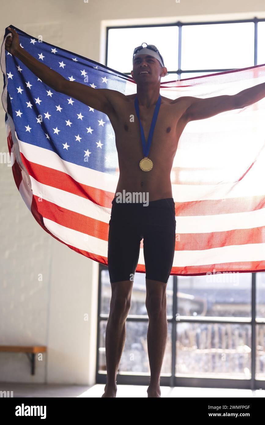 Young biracial male athlete swimmer celebrates victory with an American ...