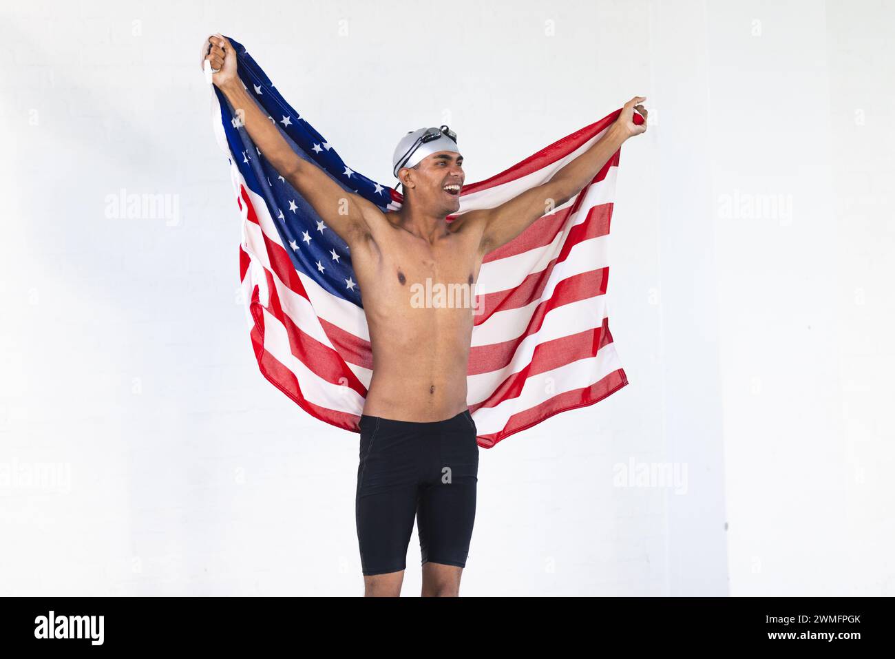 Young biracial male athlete swimmer celebrates with an American flag ...