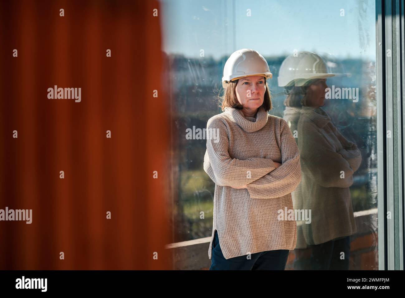 Female architect wearing white hardhat posing on construction site ...
