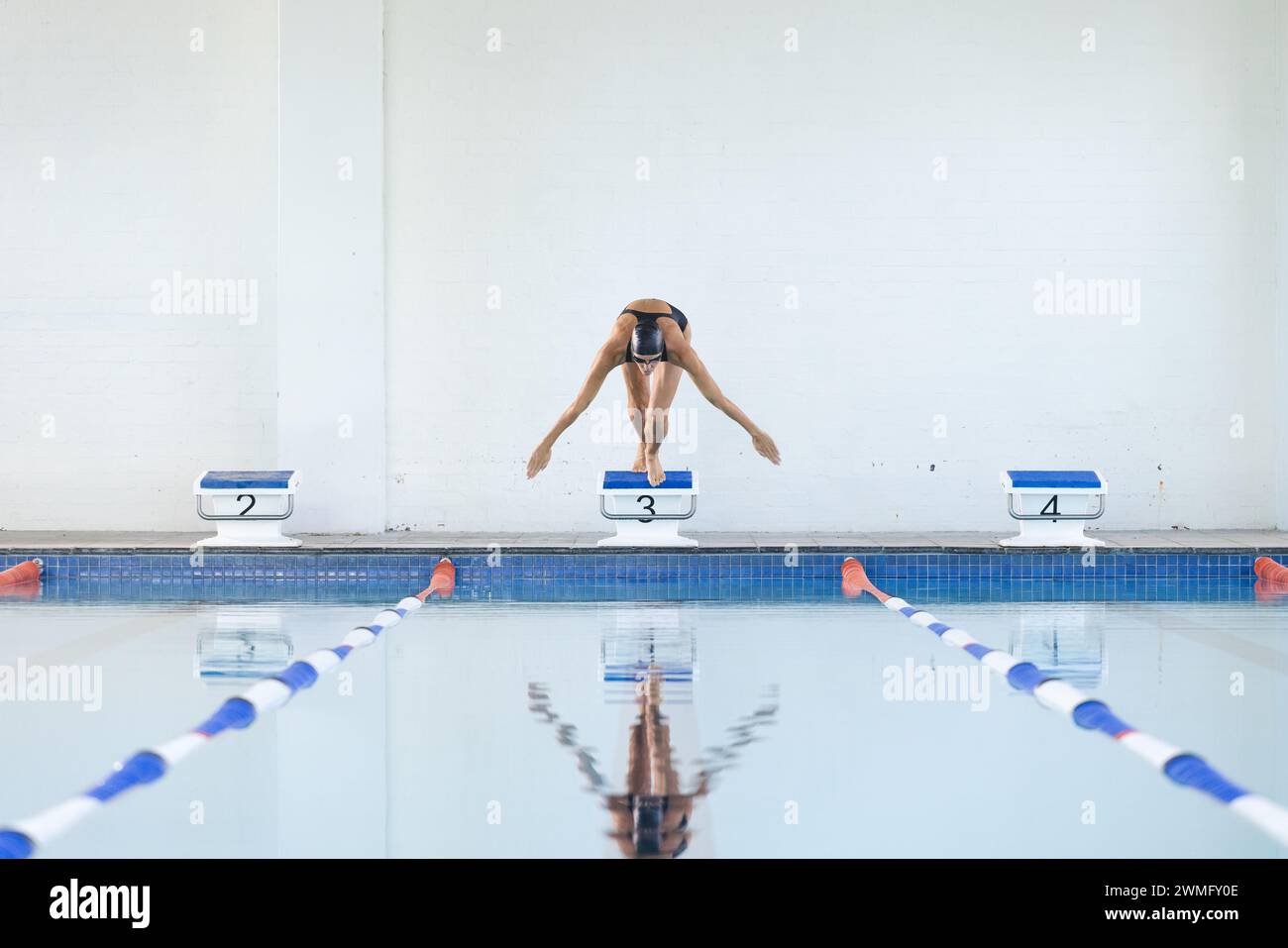 Athlete dives into a swimming pool at a sports facility. Perfect form ...