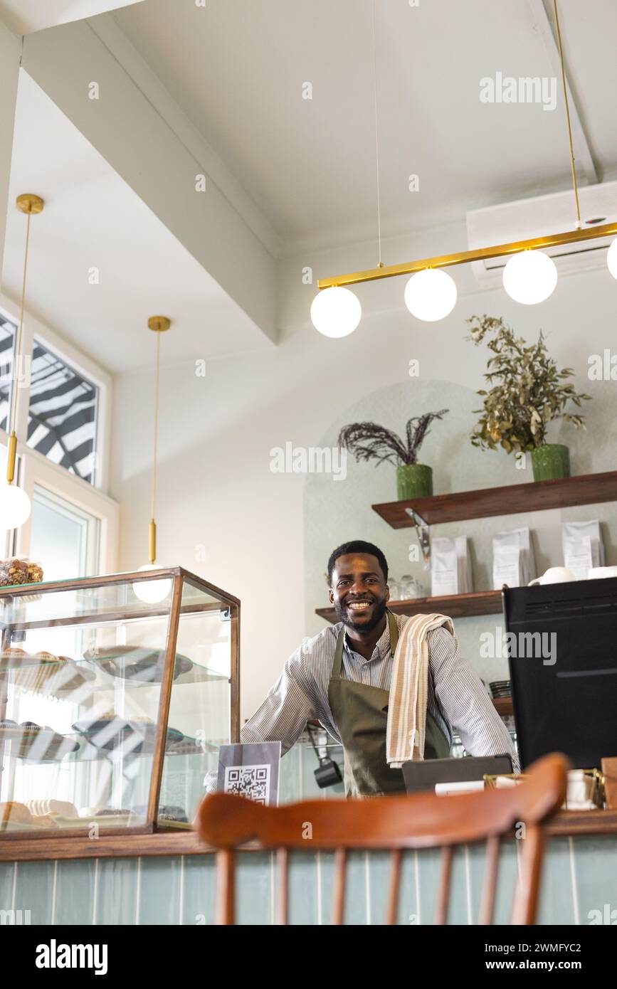 An African American male barista stands behind a cafe counter, with ...