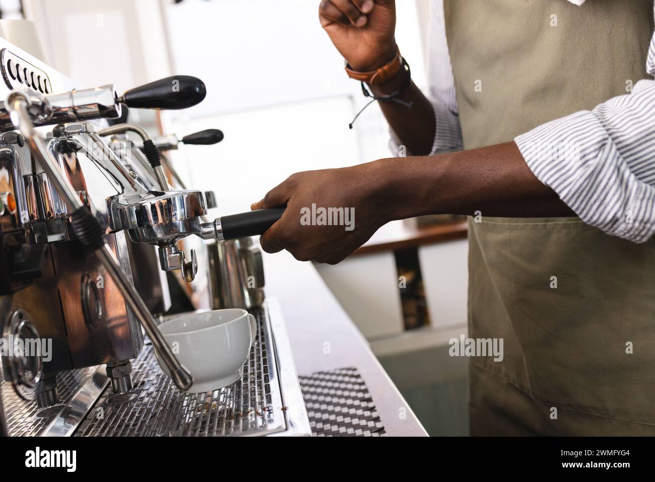An African American barista prepares coffee at an espresso machine ...