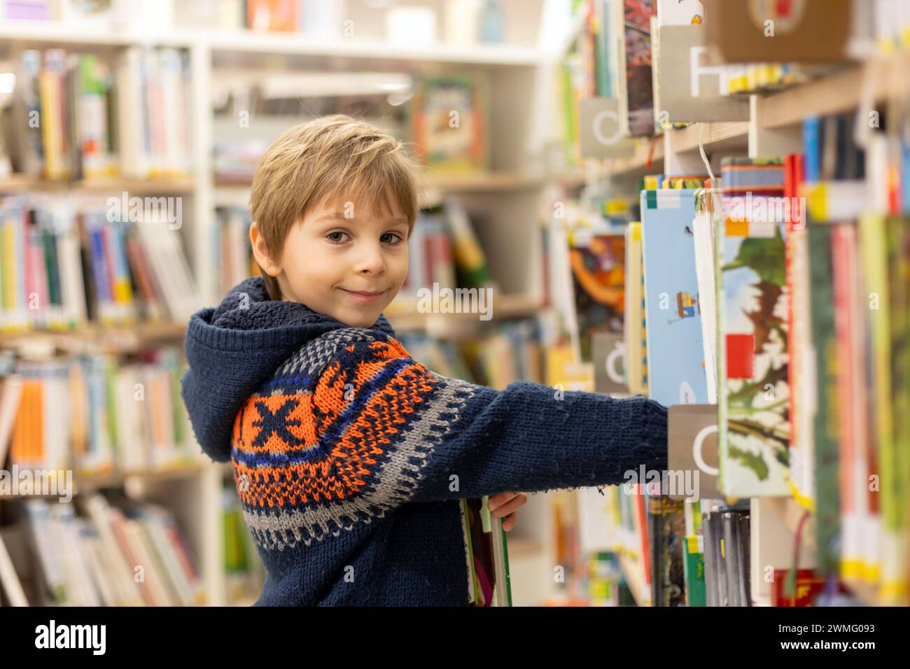 Smart child, school boy, educating himself in a library, borrowing ...
