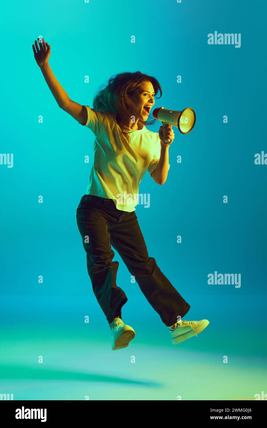 Full-length portrait young lady shouting important news to megaphone in ...