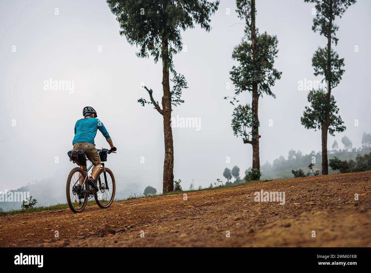 Mountain biker cycles along gravel road in the mountains of Rwanda ...