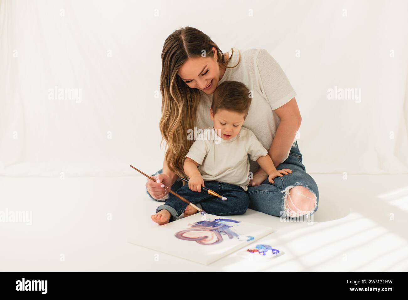 Mother and child painting on canvas together on white background Stock ...