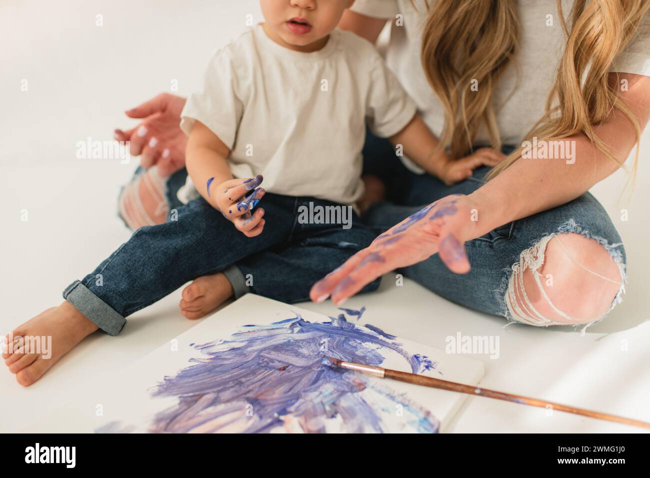 Close up of mother and son with paint on hands while painting together ...