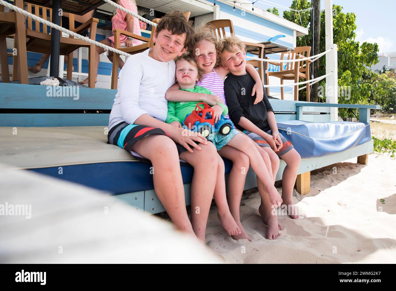 Four Smiling Siblings Sit Together on Caribbean Beach Bar Patio Stock ...