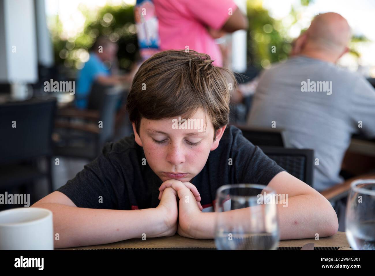 Young Contemplative Tween Boy Sits at Table at Restaurant Stock Photo ...