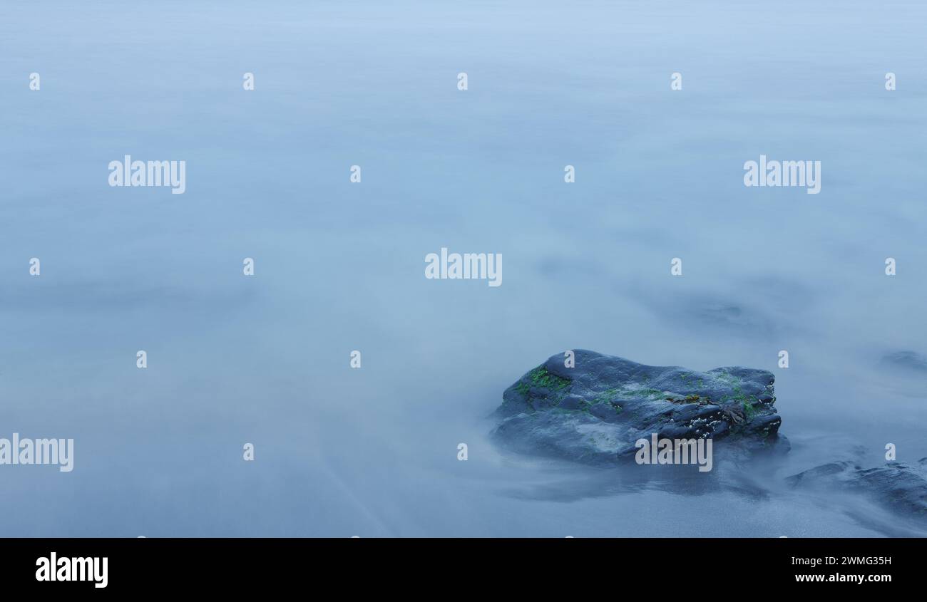 Rock in blurred out sea due to long-exposure phothgraph Stock Photo - Alamy