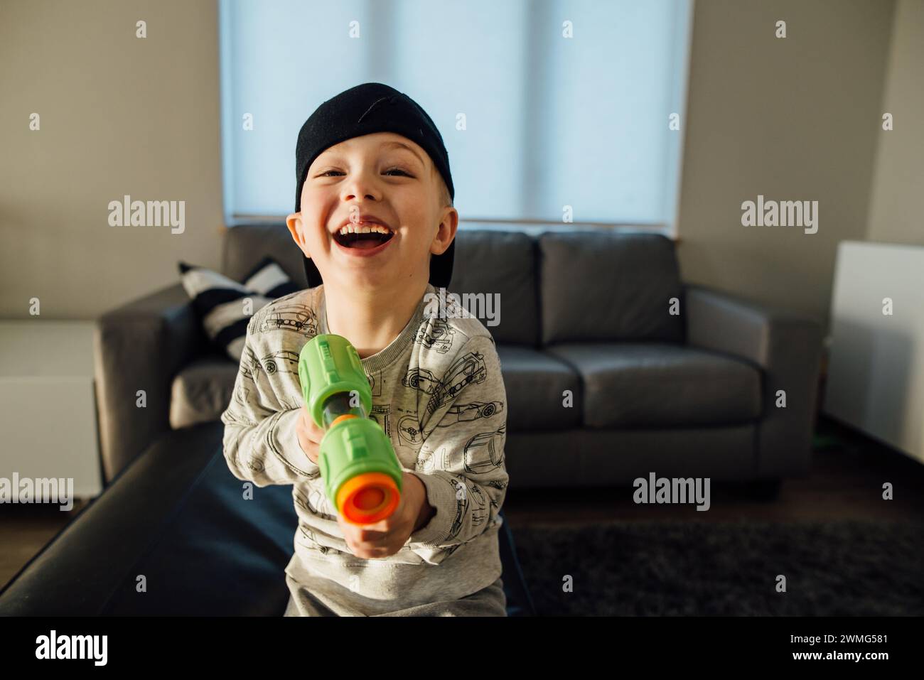 Close up of young boy laughing at camera while holding toy gun Stock ...