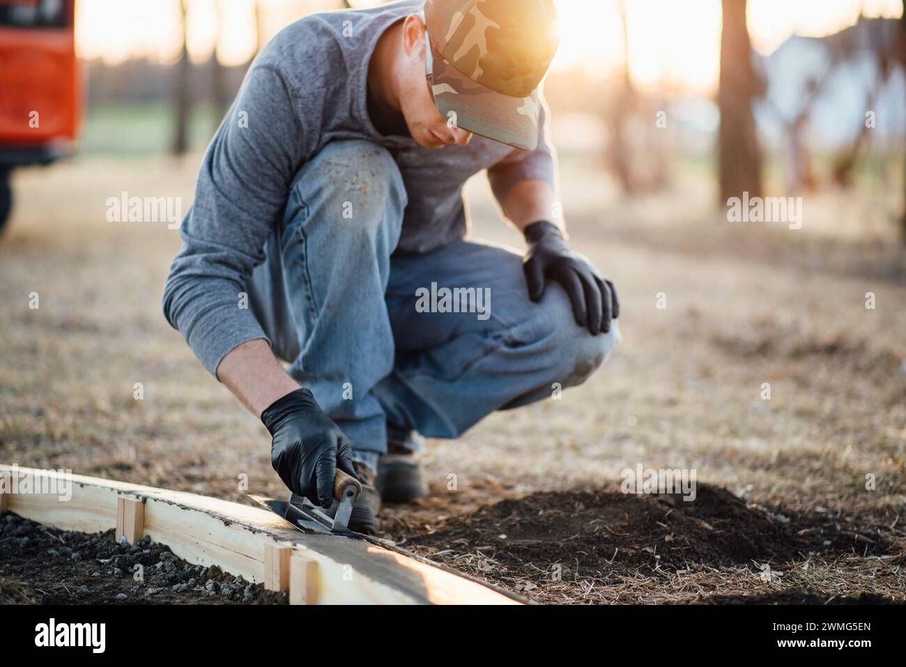 Wide front view of man kneeling while using trowel on concrete Stock ...