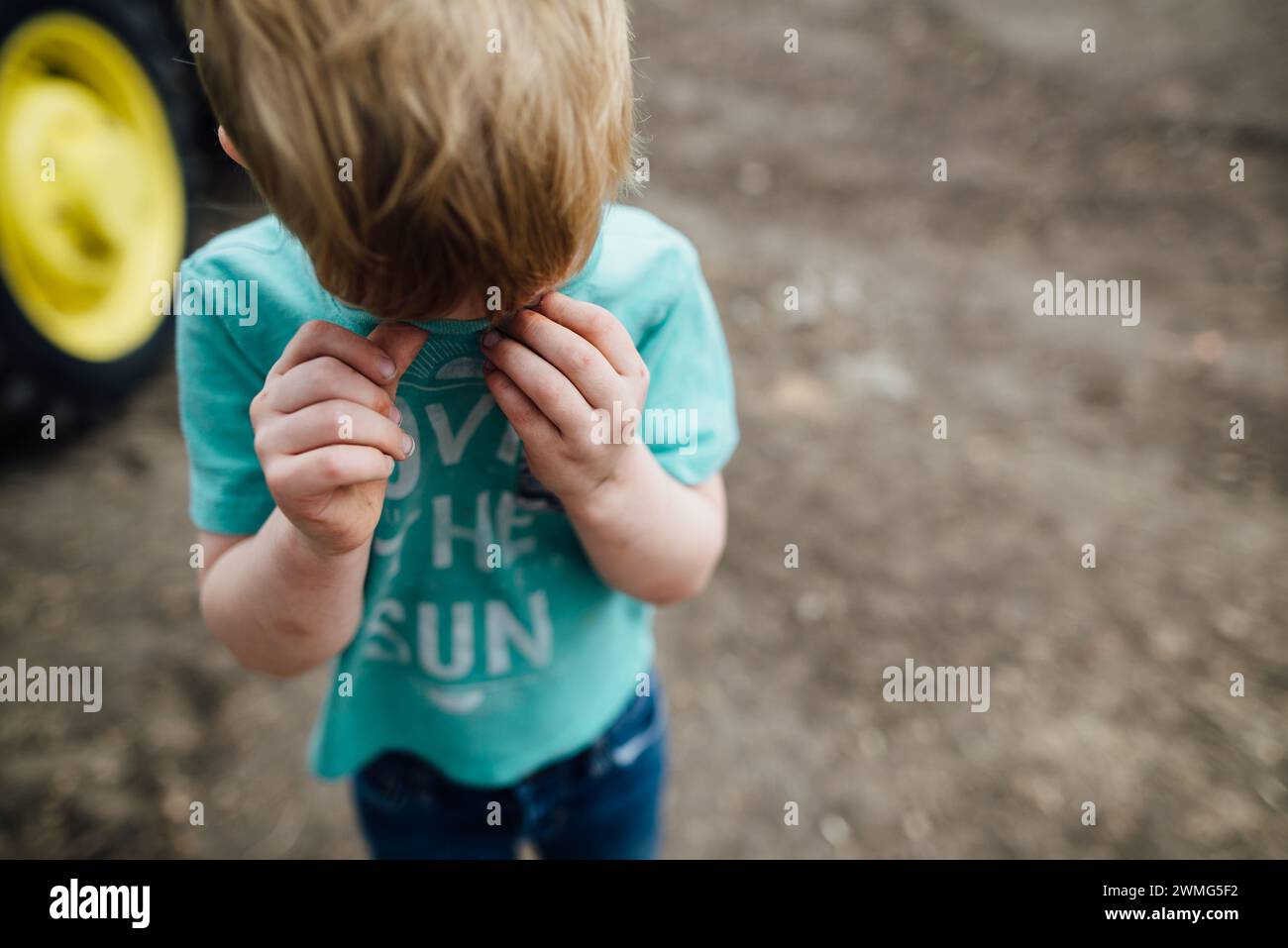 Overhead view of young boy using a shirt to wipe his face Stock Photo ...