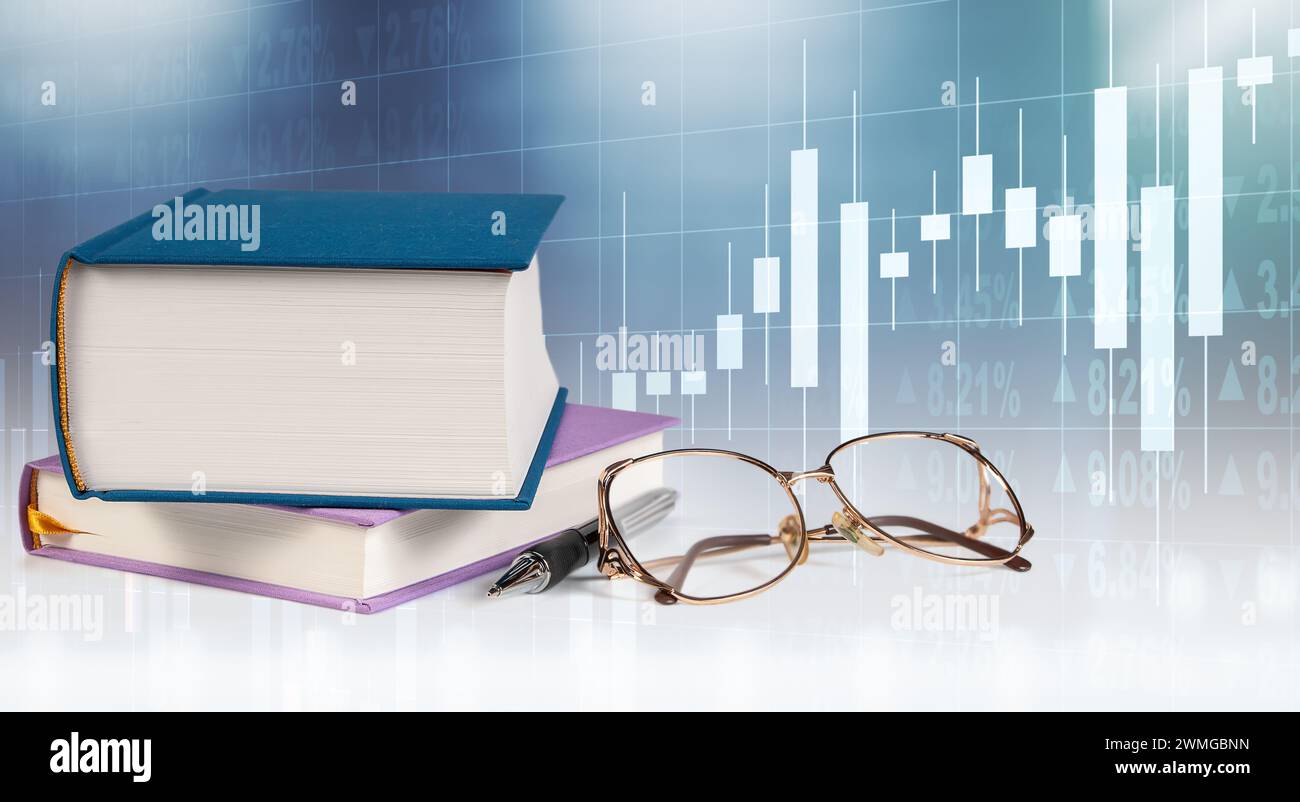 A collection of books is piled next to office supplies including pens ...