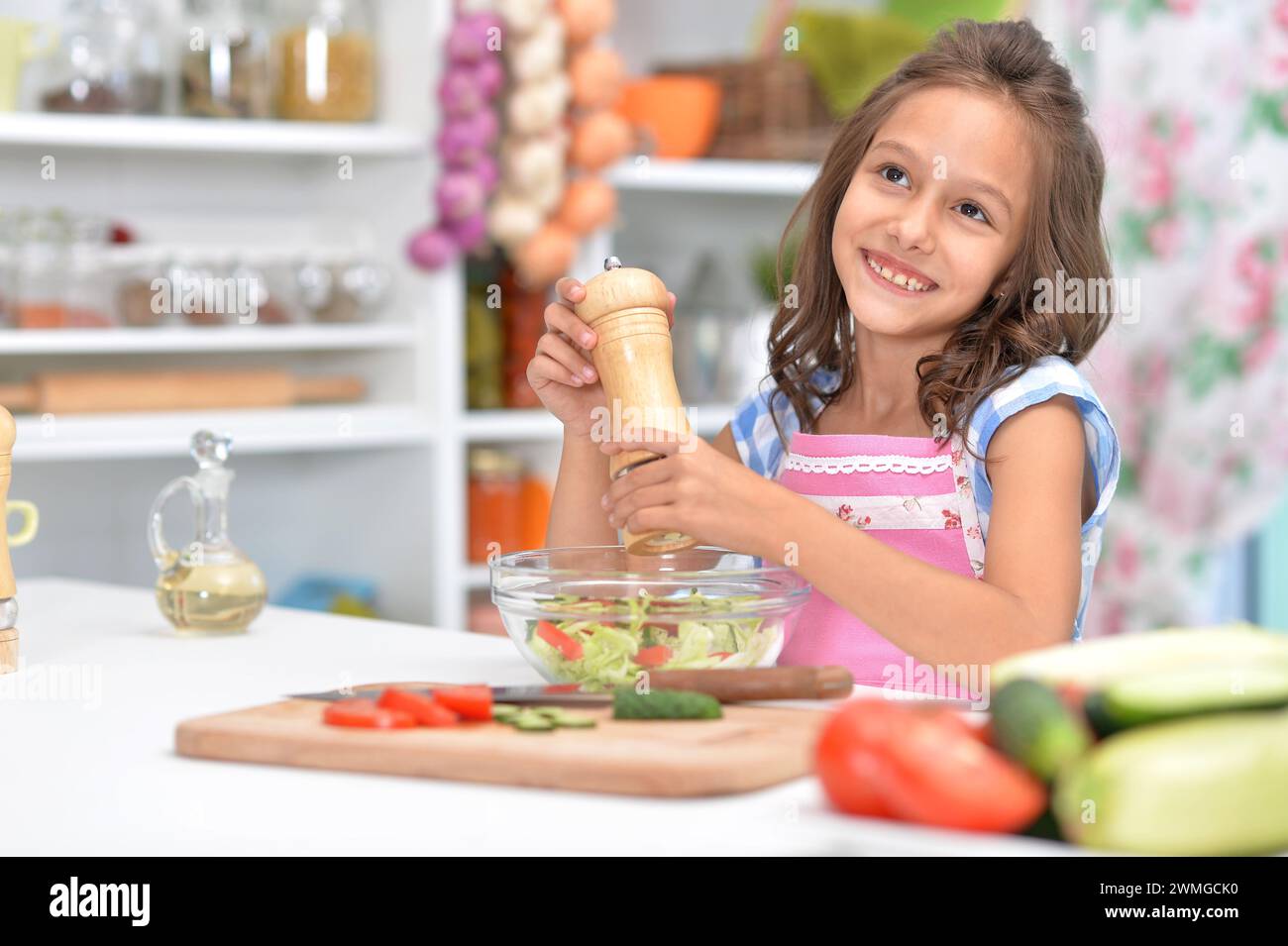 Portrait of cute little girl making dinner Stock Photo - Alamy