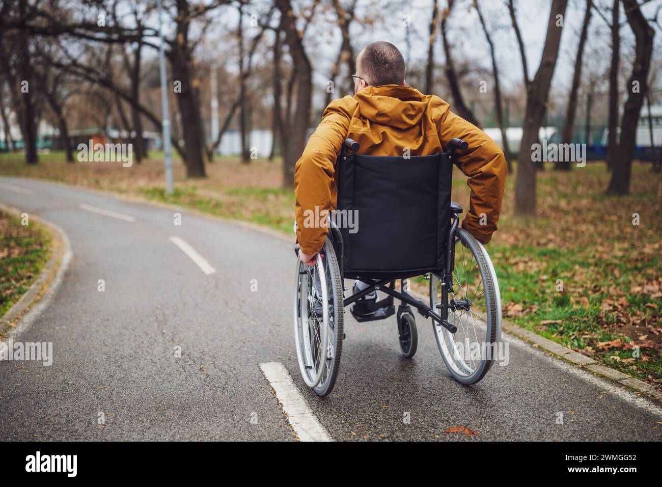 Rear view image of paraplegic handicapped man in wheelchair in park. He ...