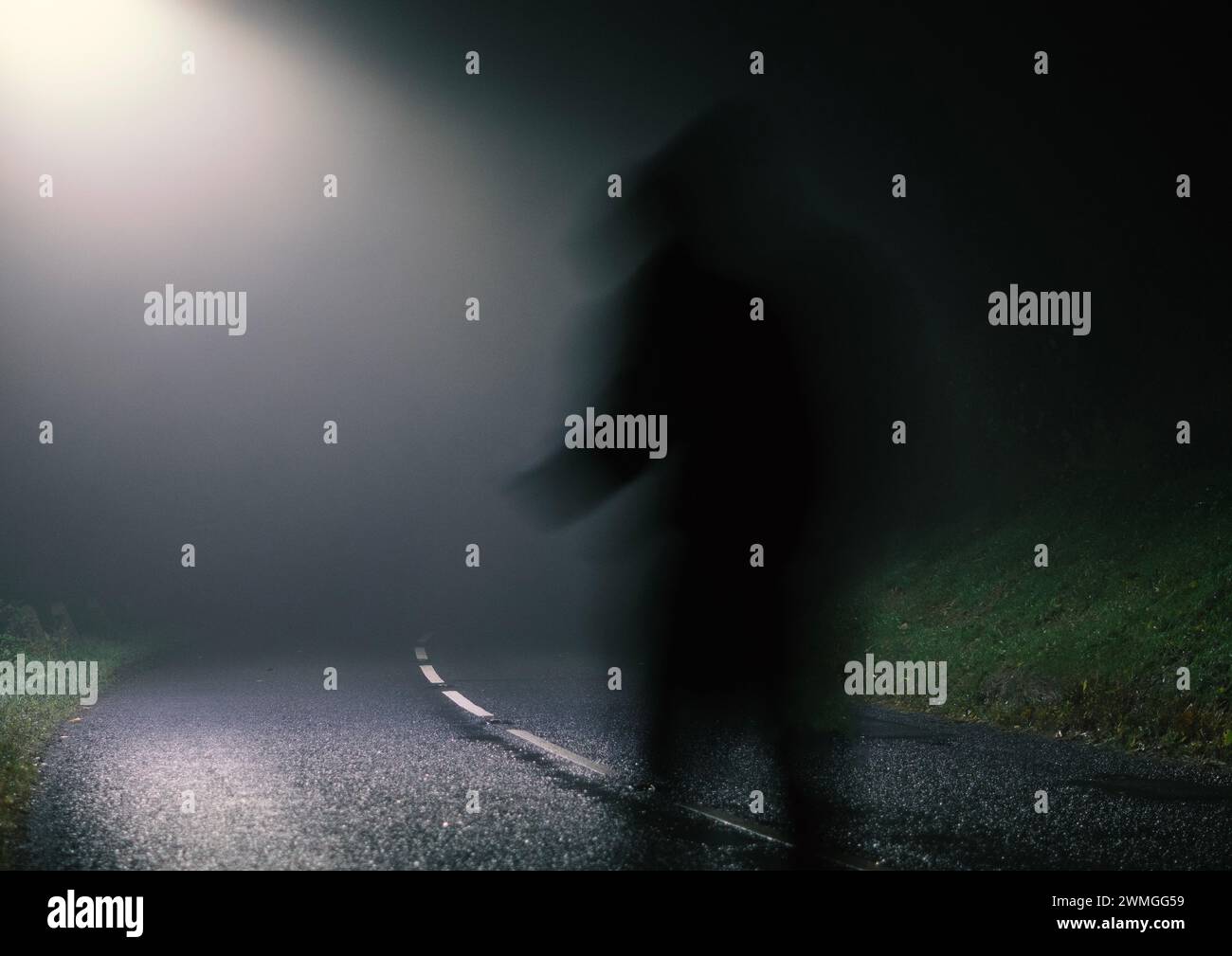A shadow ghost like figure, on an empty spooky road at night. With a ...