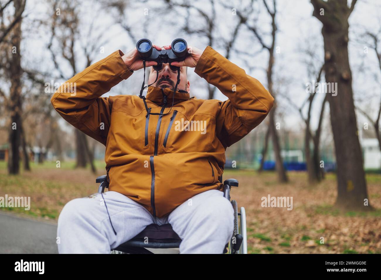 Paraplegic handicapped man in wheelchair is using binoculars outdoor ...